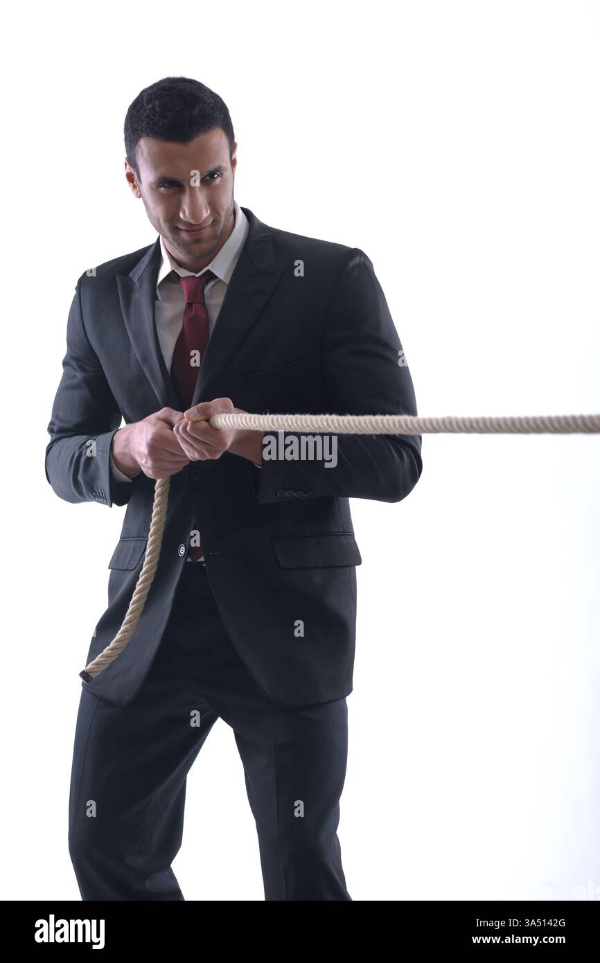 Serious Middle Eastern businessman pulling rope on white background in ...