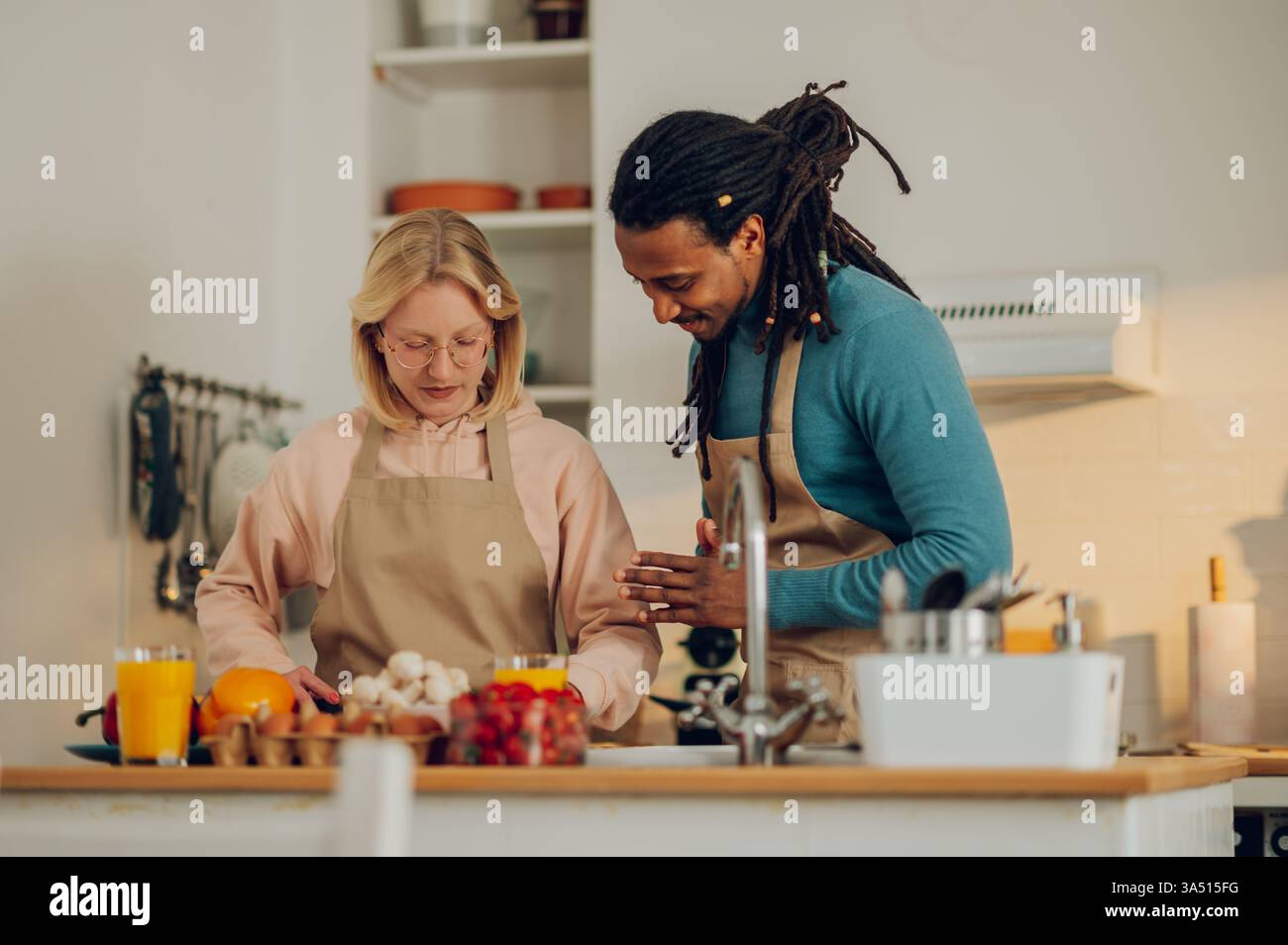 The partners are standing in the kitchen and preparing a healthy veggie ...