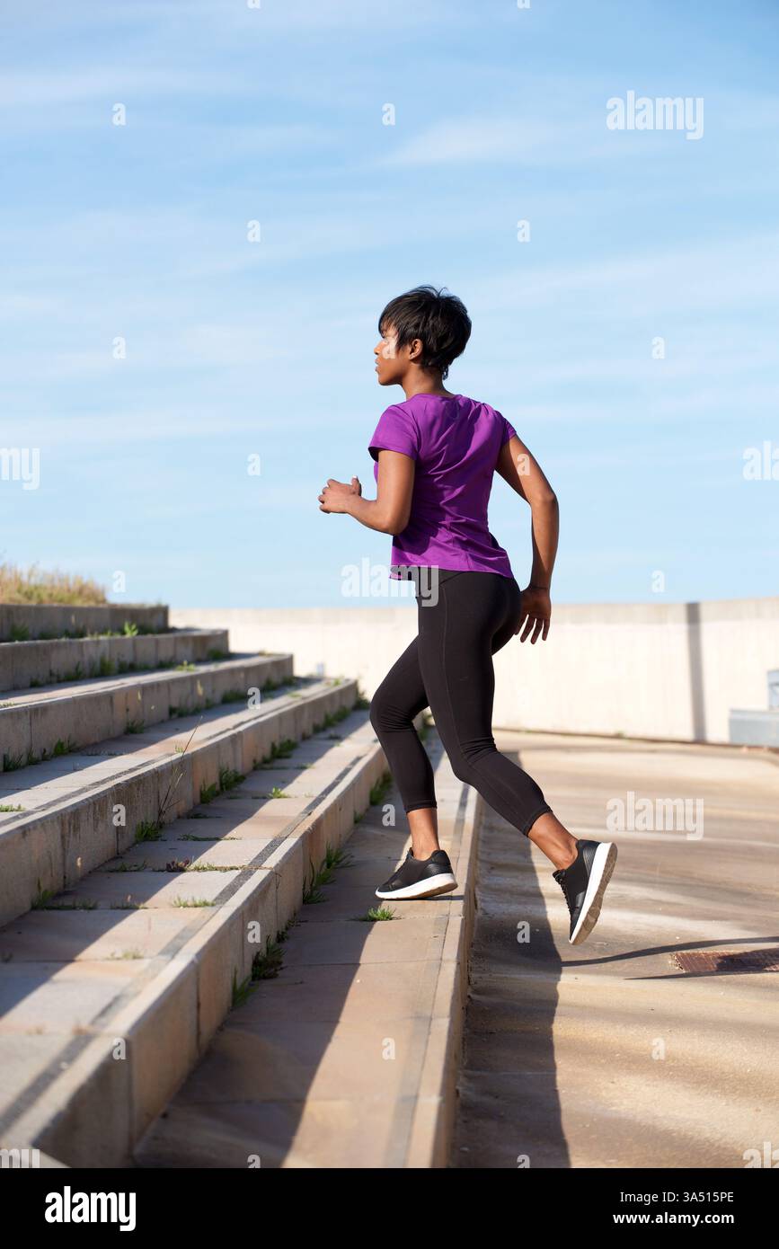 Full length side portrait of fit young sports woman running on steps ...