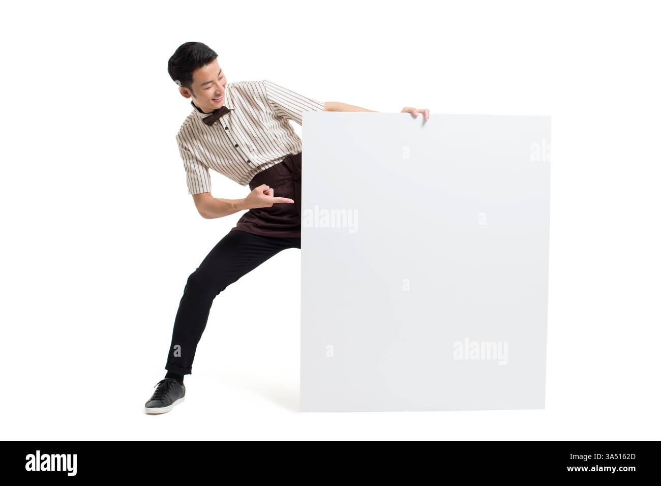 Smiling Chinese male waiter pointing and looking at whiteboard while ...