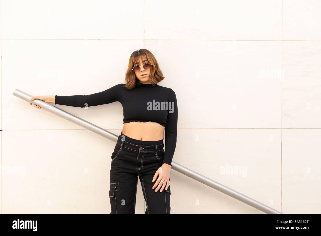 A stylish Hispanic woman in a black crop top and pants poses ...