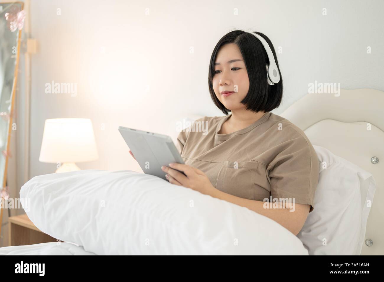 A beautiful Asian plus-size woman in casual clothes wearing headphones ...