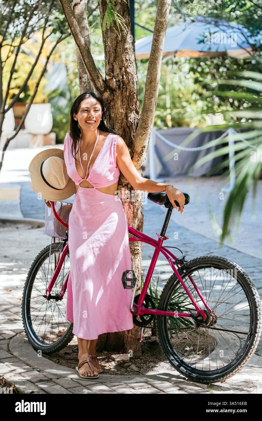 Full body of positive young mixed race female in summer dress and straw ...