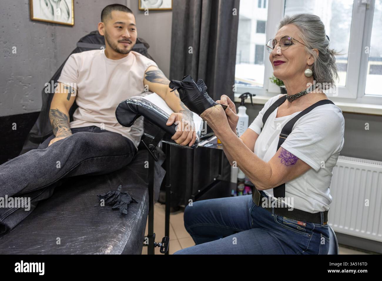Female tattooist. Mature female tattoo master working with the customer ...