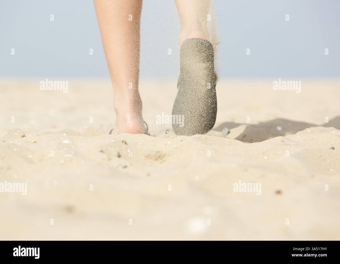 Low angle from behind view of woman walking with flip flops on beach ...
