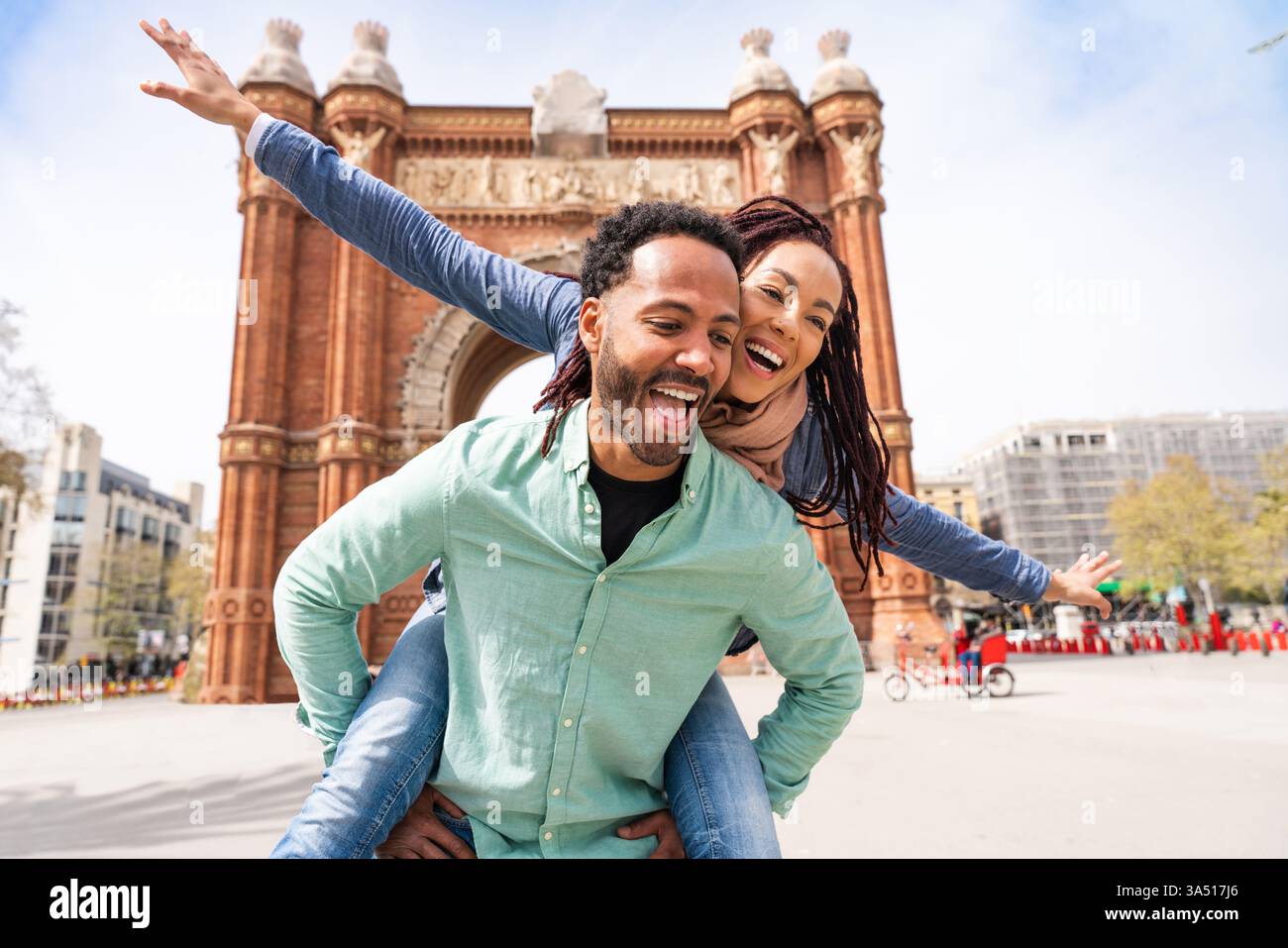 Cheerful Hispanic male giving piggy back ride to Hispanic girlfriend with outstretched arms ...