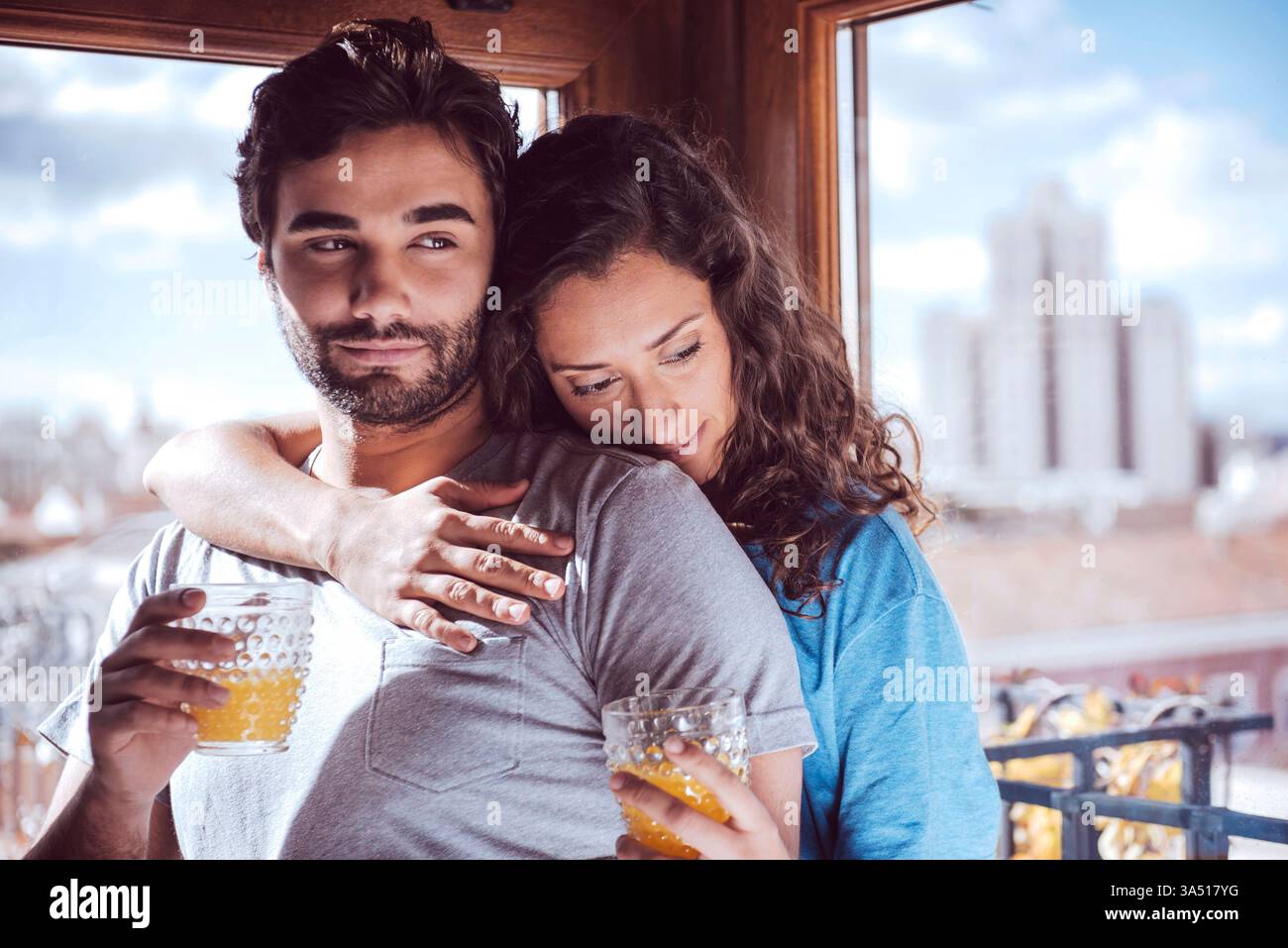 Hispanic woman embracing boyfriend from behind standing near window at ...