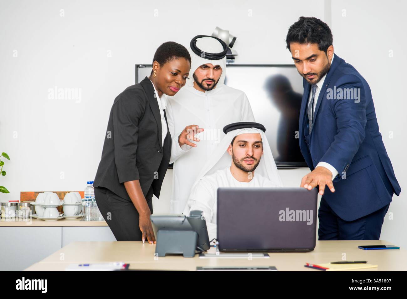 Multicultural group of professionals in a UAE office gather for a ...