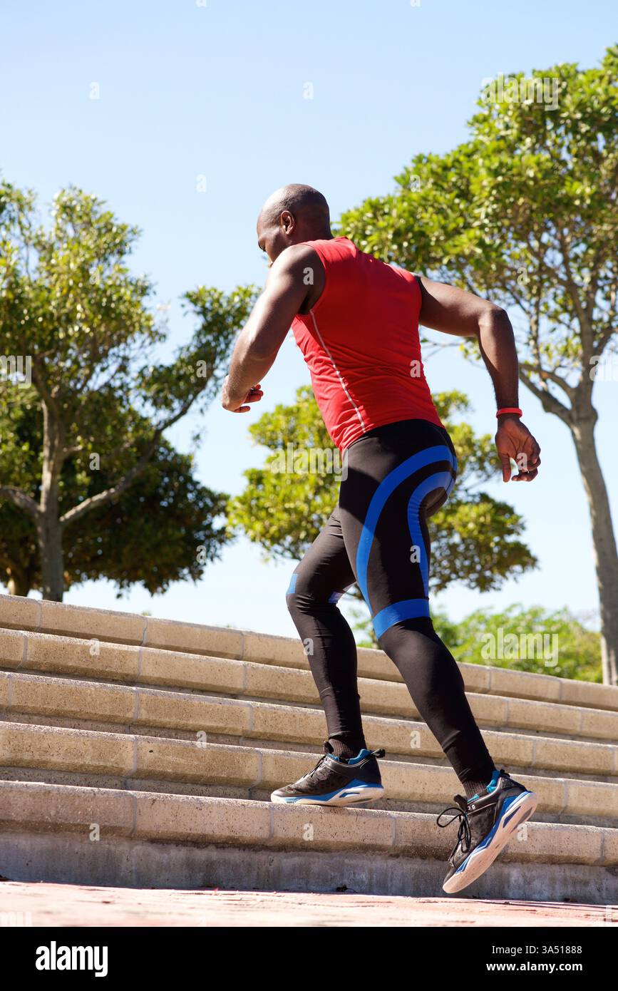 Determined muscular Black man running on stairs in park on sunny day ...