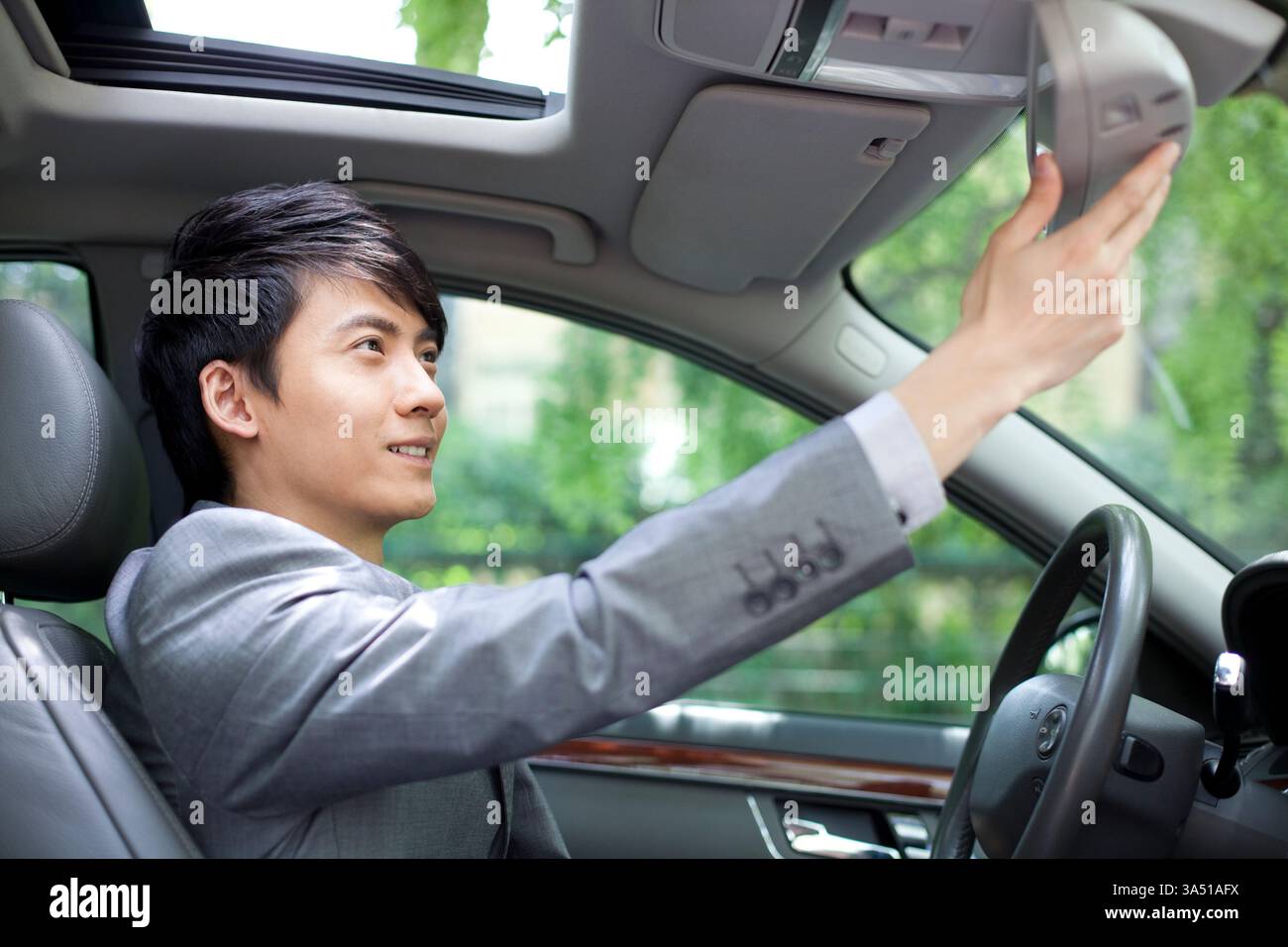 Chinese businessman adjusting rear view mirror sitting in car Stock ...