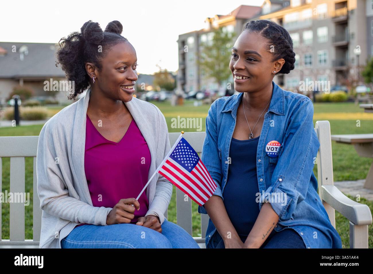Young black women wearing Voting pin sitting on a bench in public park ...
