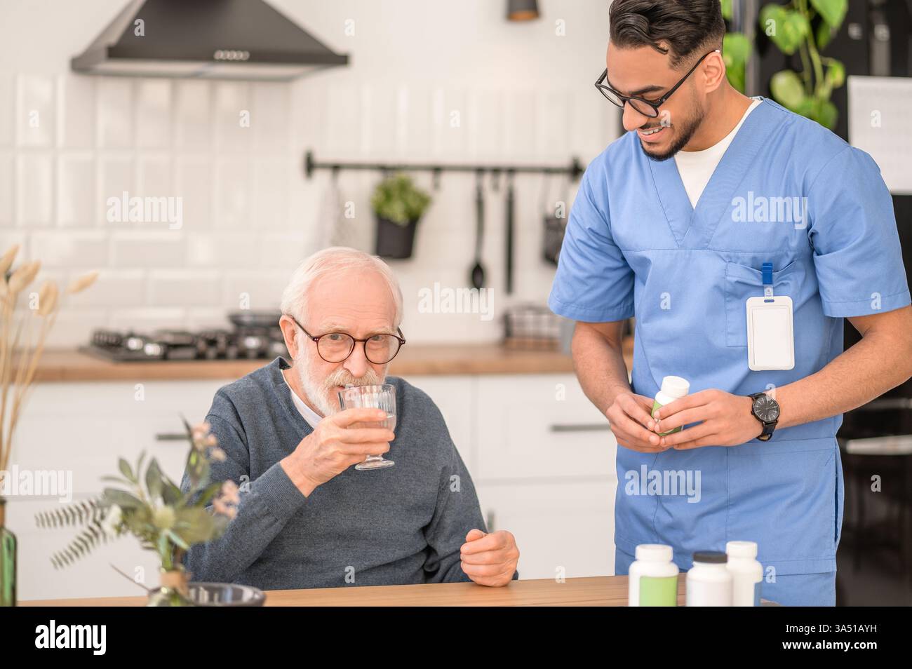 Caring male nurse in uniform watching an elderly man washing down his ...
