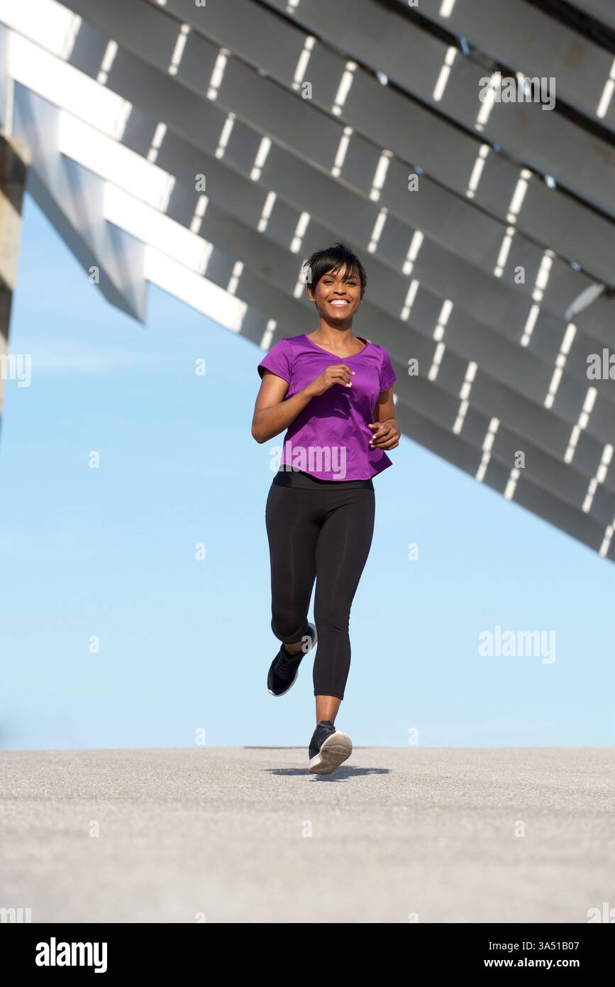 Full body portrait of healthy young african woman running outdoors ...