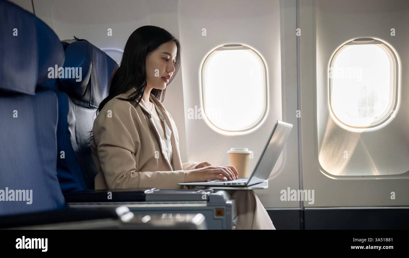 Serious Asian business woman using laptop sitting with crossed legs in ...