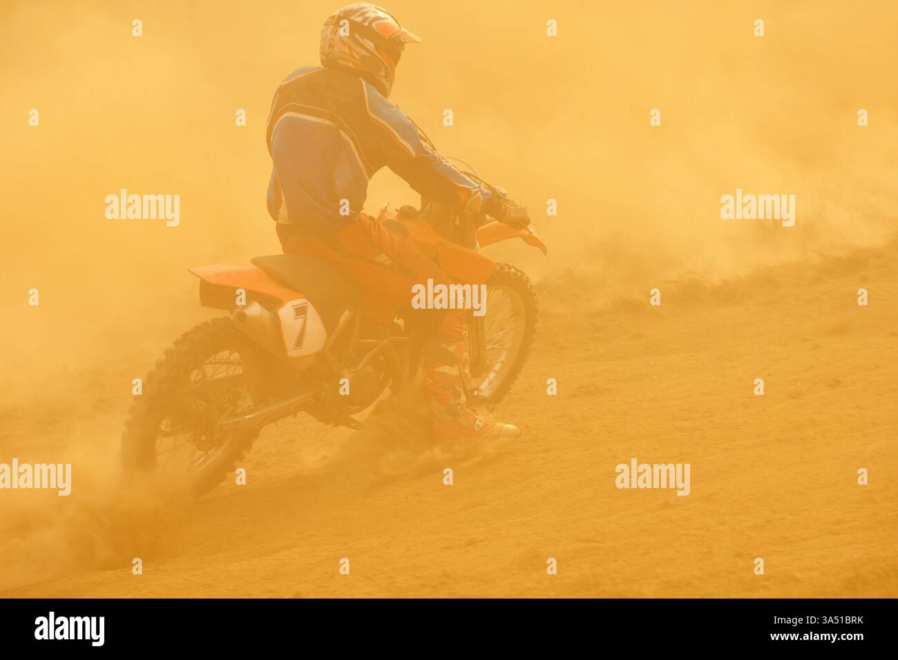 Male motocross rider in safety gears riding motorcycle on sand track on ...
