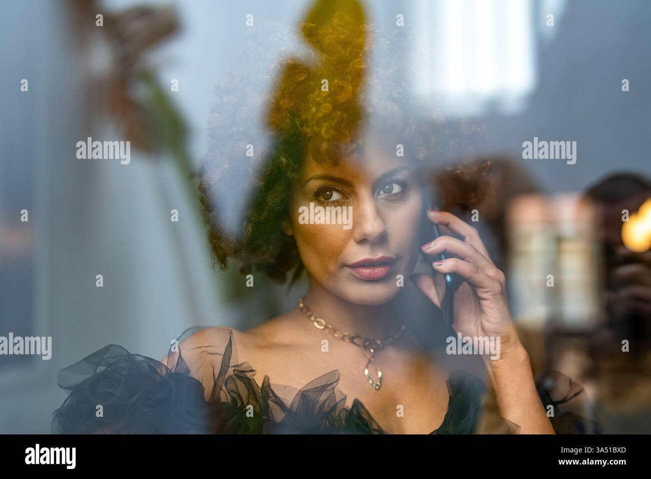 Serious Middle Eastern woman with afro taking phone call while standing ...