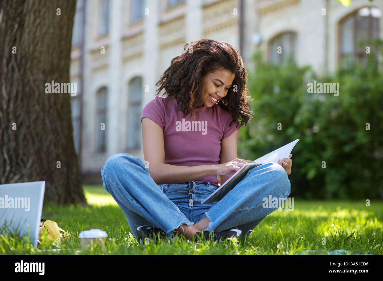 African American female student reading notes in notebook sitting with ...