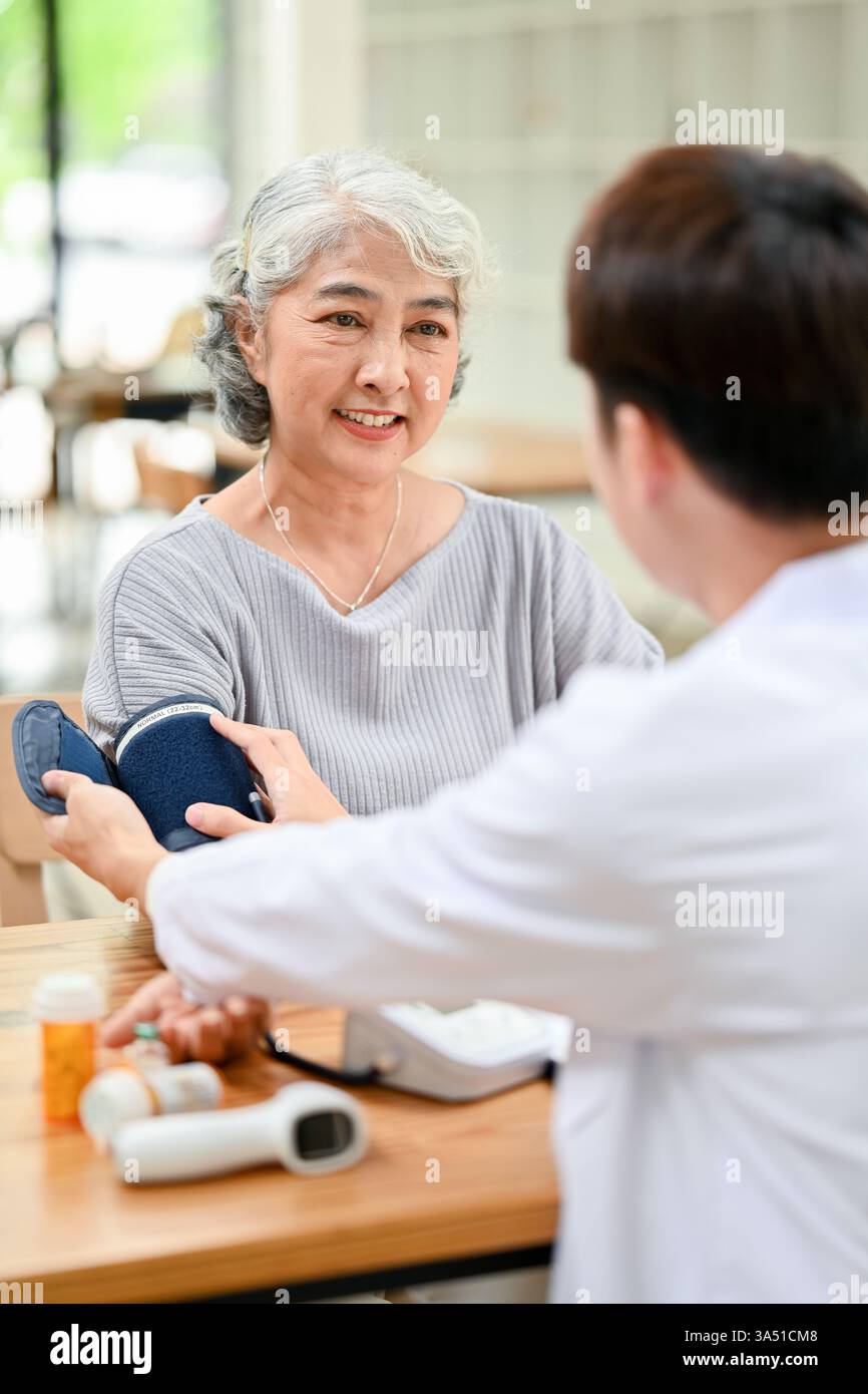 A happy Asian retired old lady is being measured for her heart rate and ...