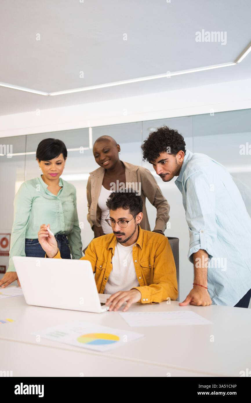 Diverse group of coworkers gathering together at table to work on ...