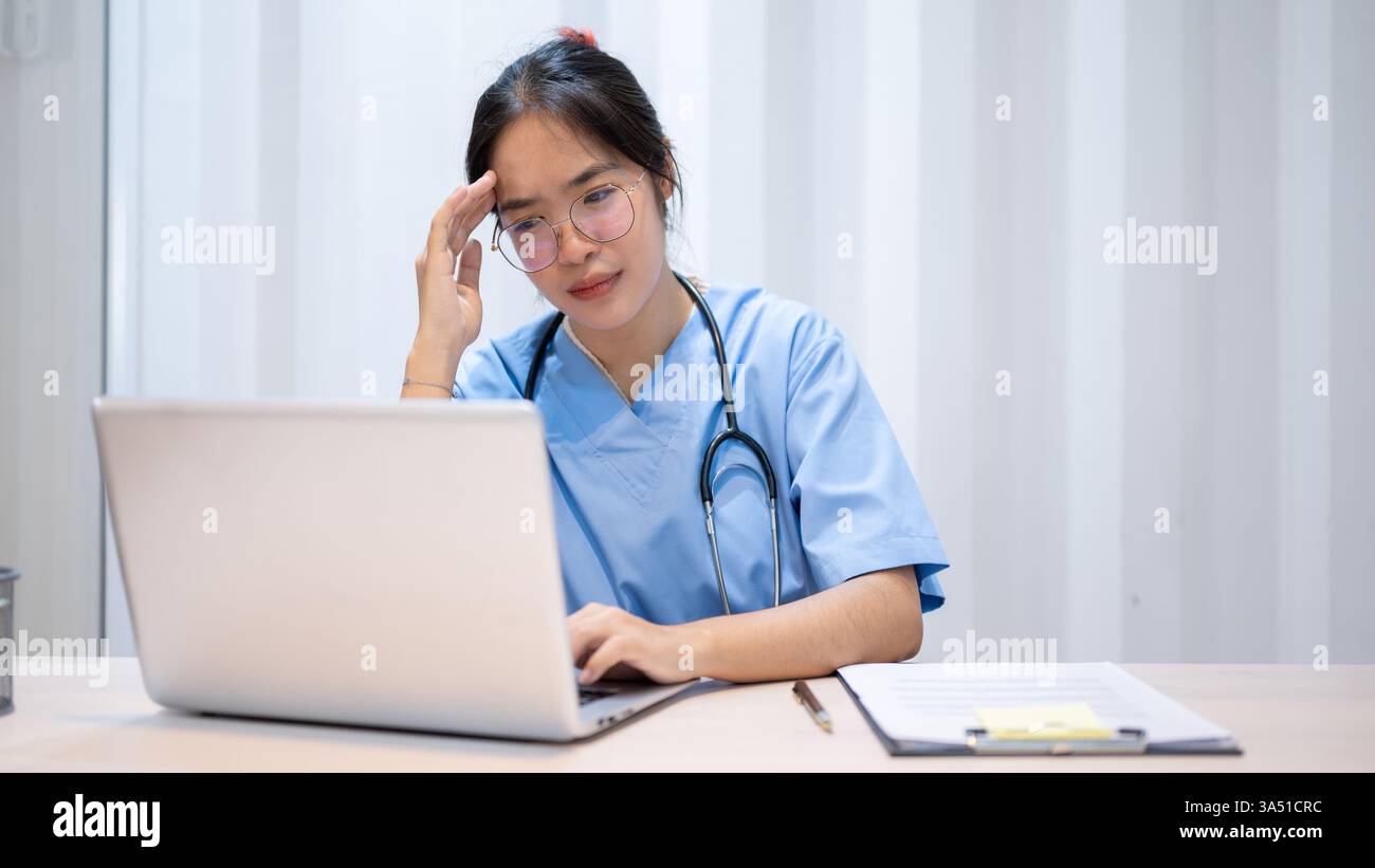 A stressed, overworked, and tired Asian female doctor is reading her ...