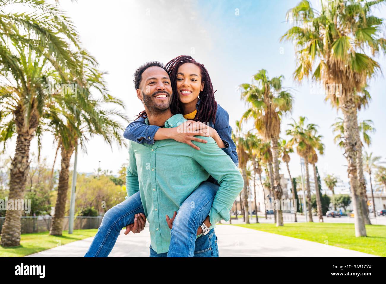Smiling Hispanic male giving piggyback ride to Hispanic girlfriend ...