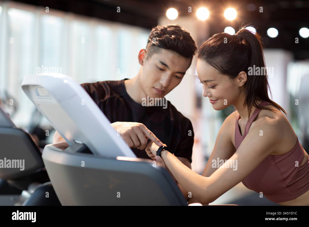 Chinese male fitness trainer setting smartwatch of female during ...