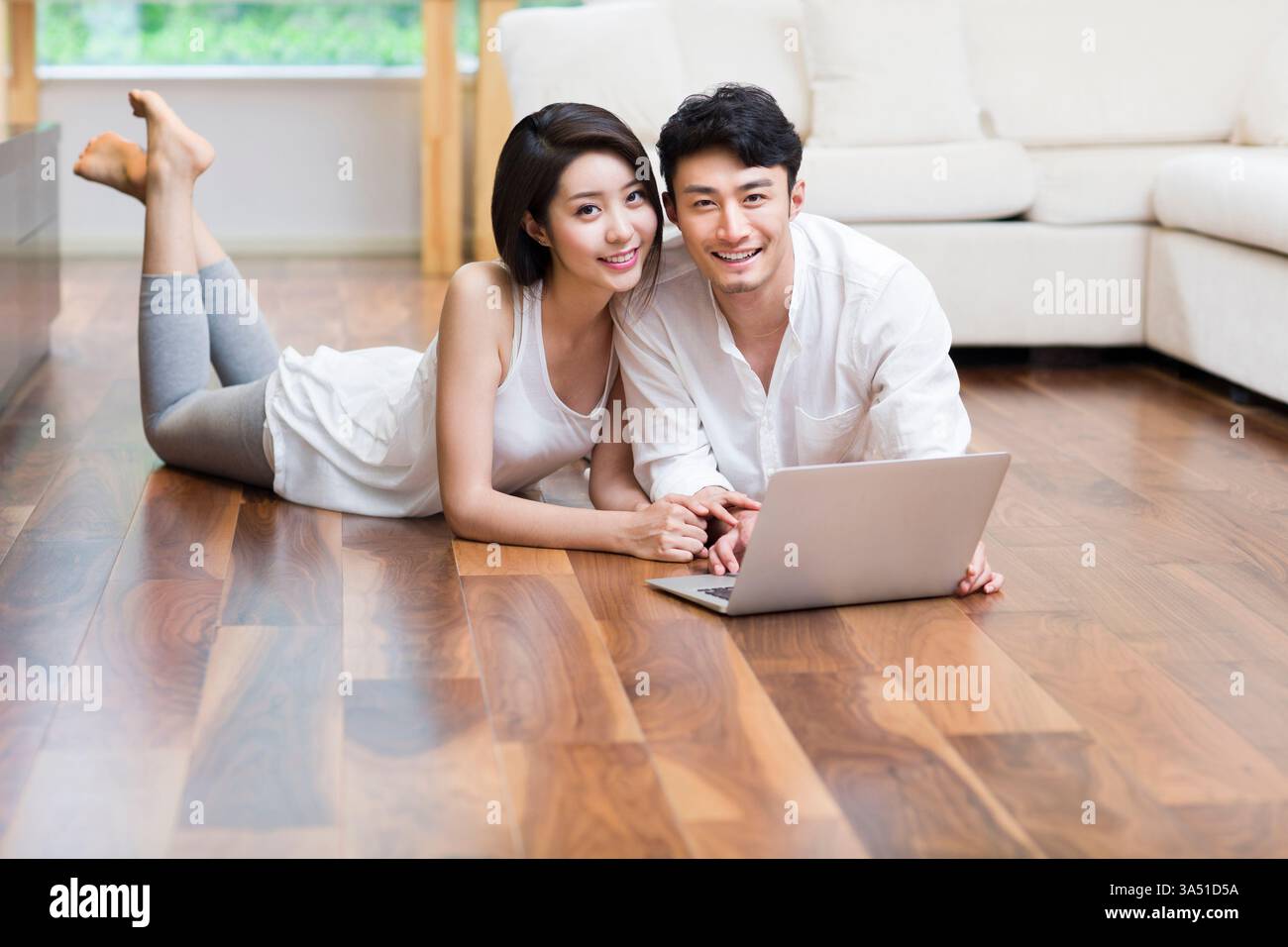 Young Chinese couple lying on floor using laptop Stock Photo - Alamy