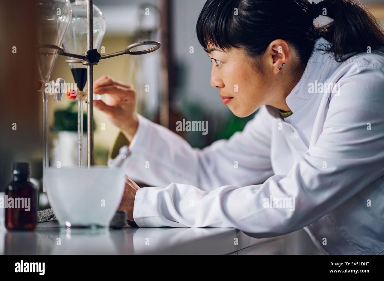 A Japanese pharmacist is making medicine in a glass funnel while ...