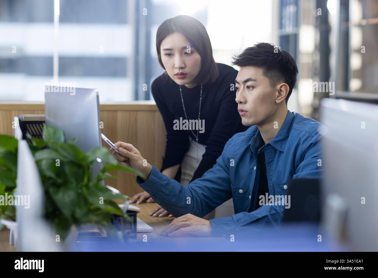 Chinese male and female IT experts working together on computer in ...