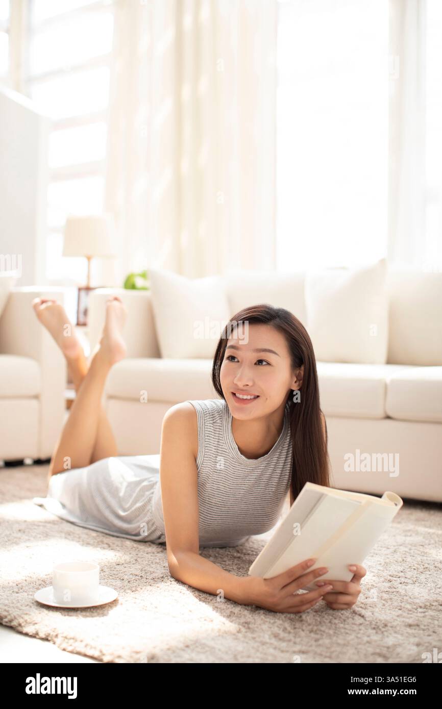 Young Chinese woman reading book in living room Stock Photo - Alamy