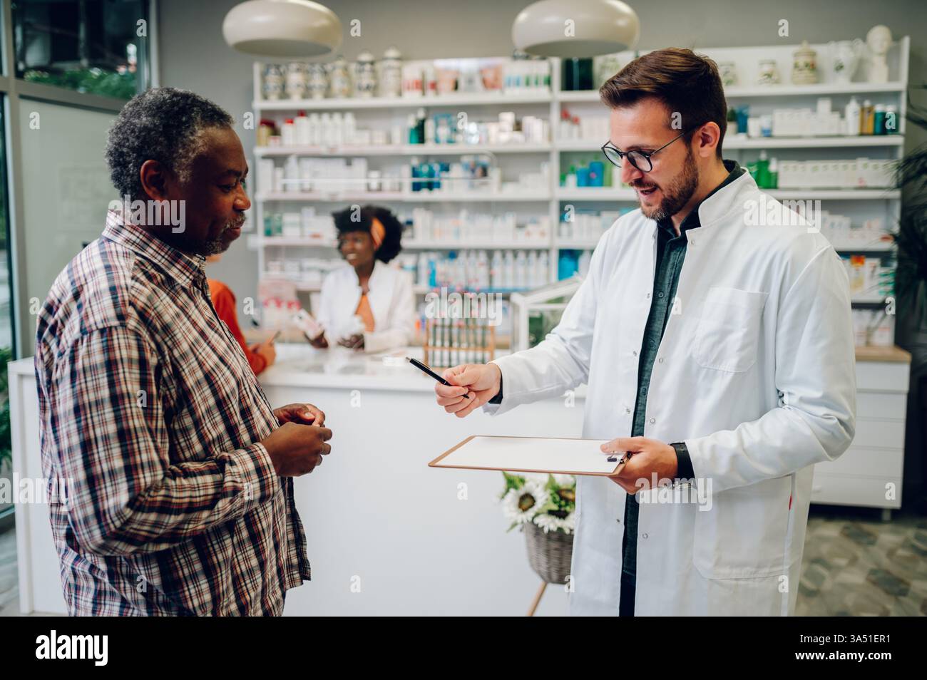 Male caucasian pharmacist working in a pharmacy and giving an african ...