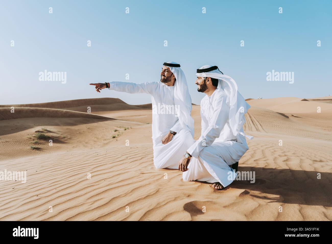 Two middle-eastern men wearing traditional emirati arab kandura bonding ...