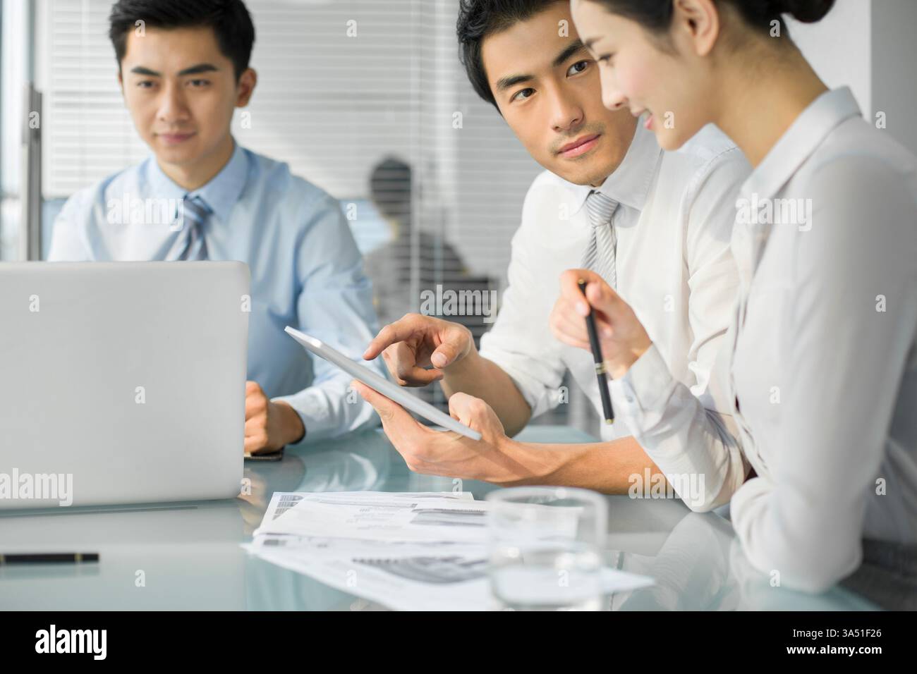 Chinese businessman pointing on tablet while talking to female ...