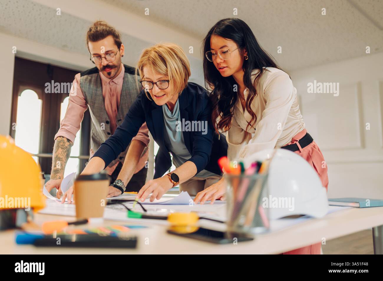 Busy Diverse group of architects working on blueprint on the table ...