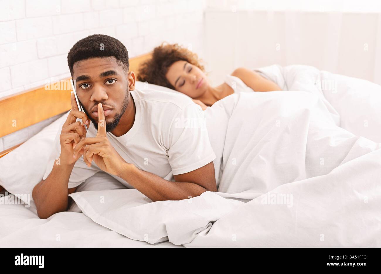 Black man cheater talking privately on cellphone in family bed, showing ...
