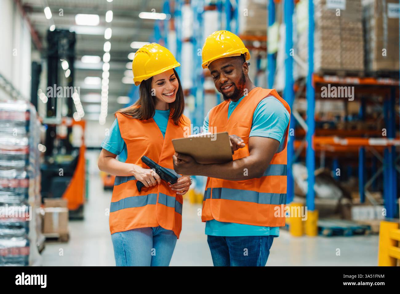 Black male worker wearing hard hat and safety vest holding clipboard ...