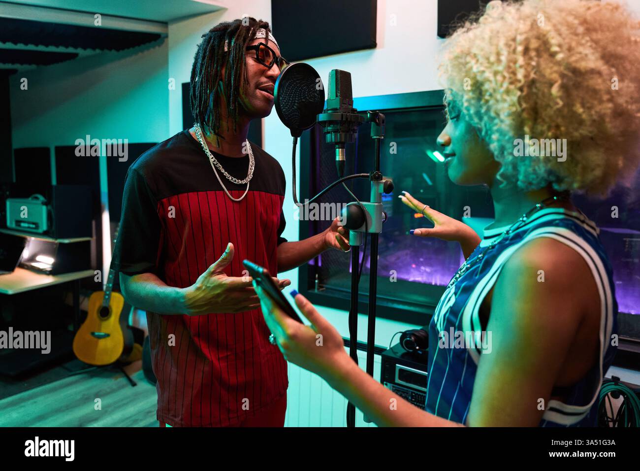 Black male singer with locks singing near microphone while standing ...