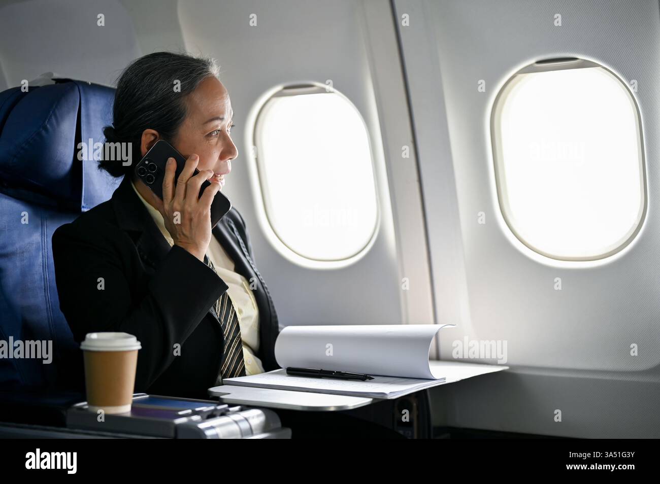 Senior Asian business woman having phone call looking away while ...