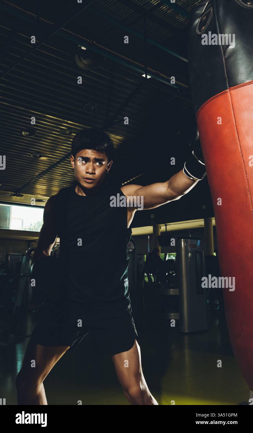 Asian male training boxing performing punches with punching bag in ...
