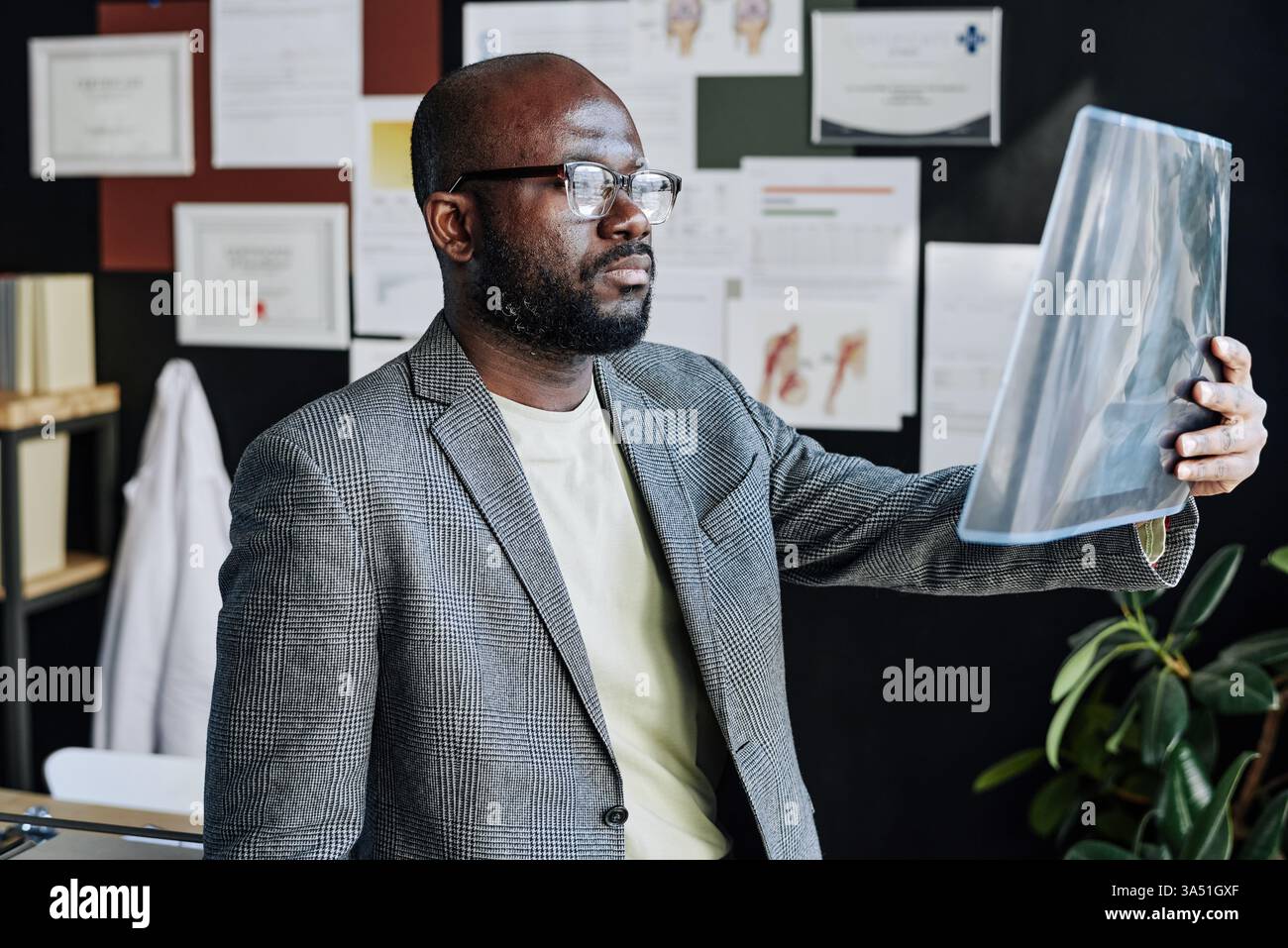 African medical specialist standing at office in front of window and ...