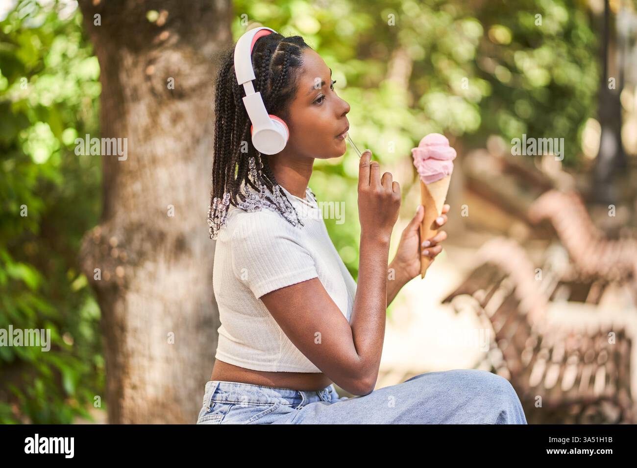 Side view of young pensive female student with headphones looking away ...