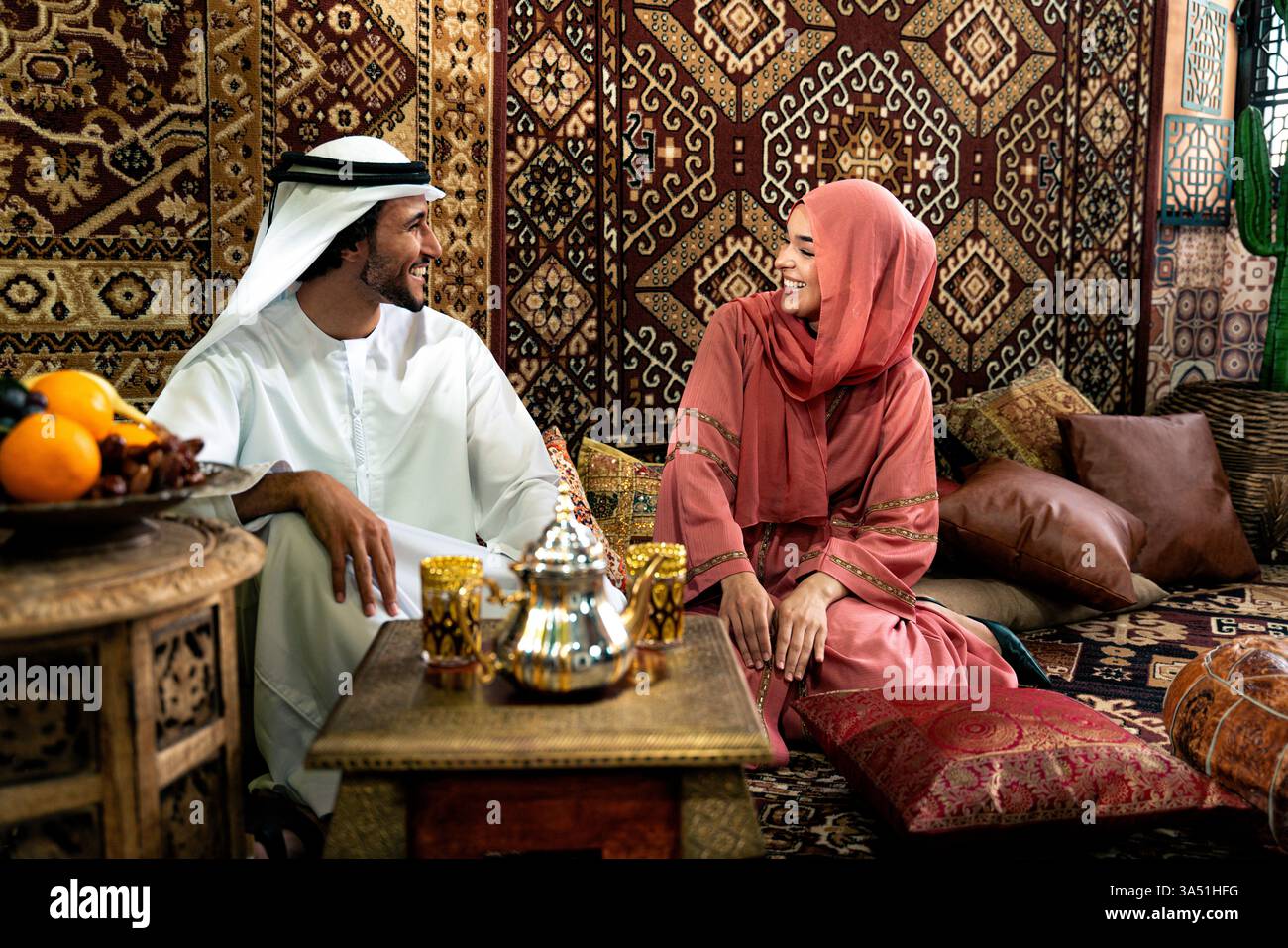Two young Emirati individuals, a man and a woman, chat in a traditional ...