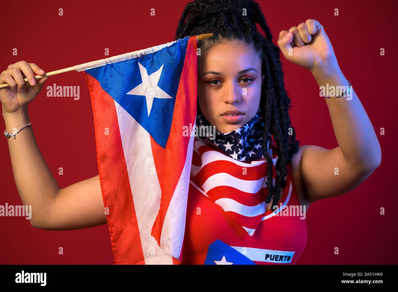 Proud Afro-Latina woman with raised fist and holding Puerto Rican flag ...