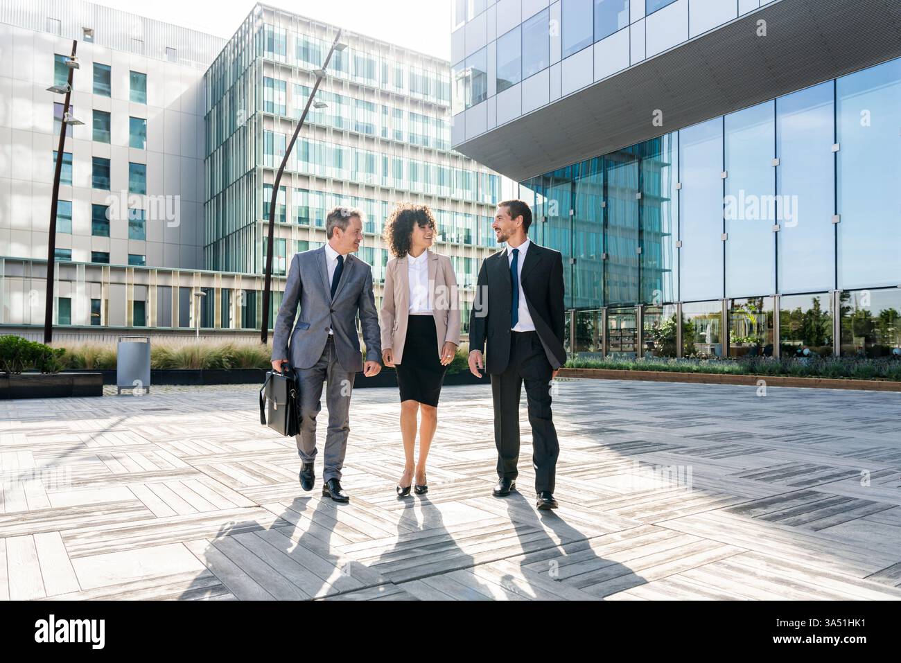 Hispanic businesswoman with caucasian male colleagues walking together ...