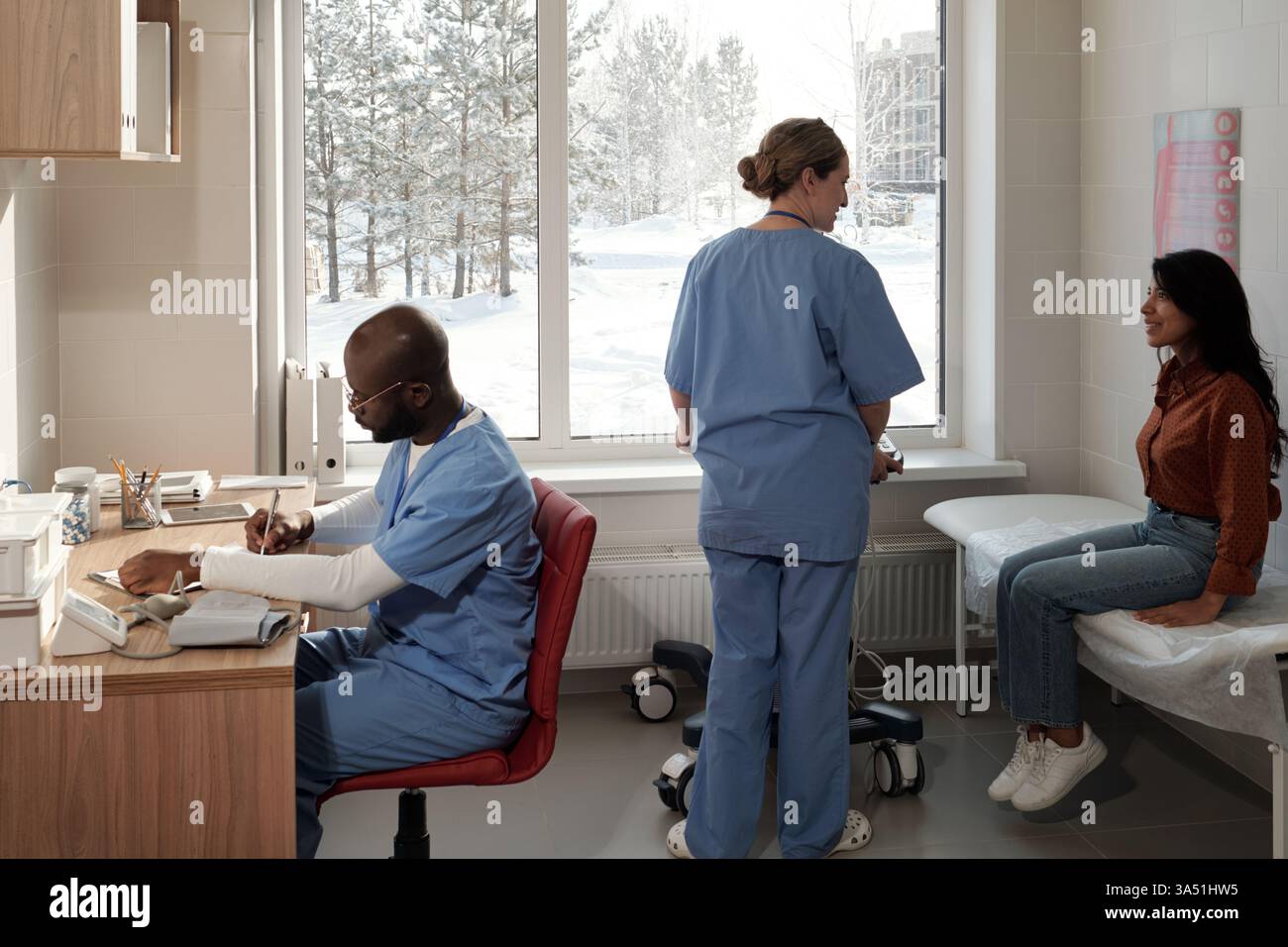 Happy Hispanic woman sitting in clinic and talking to nurse while male ...