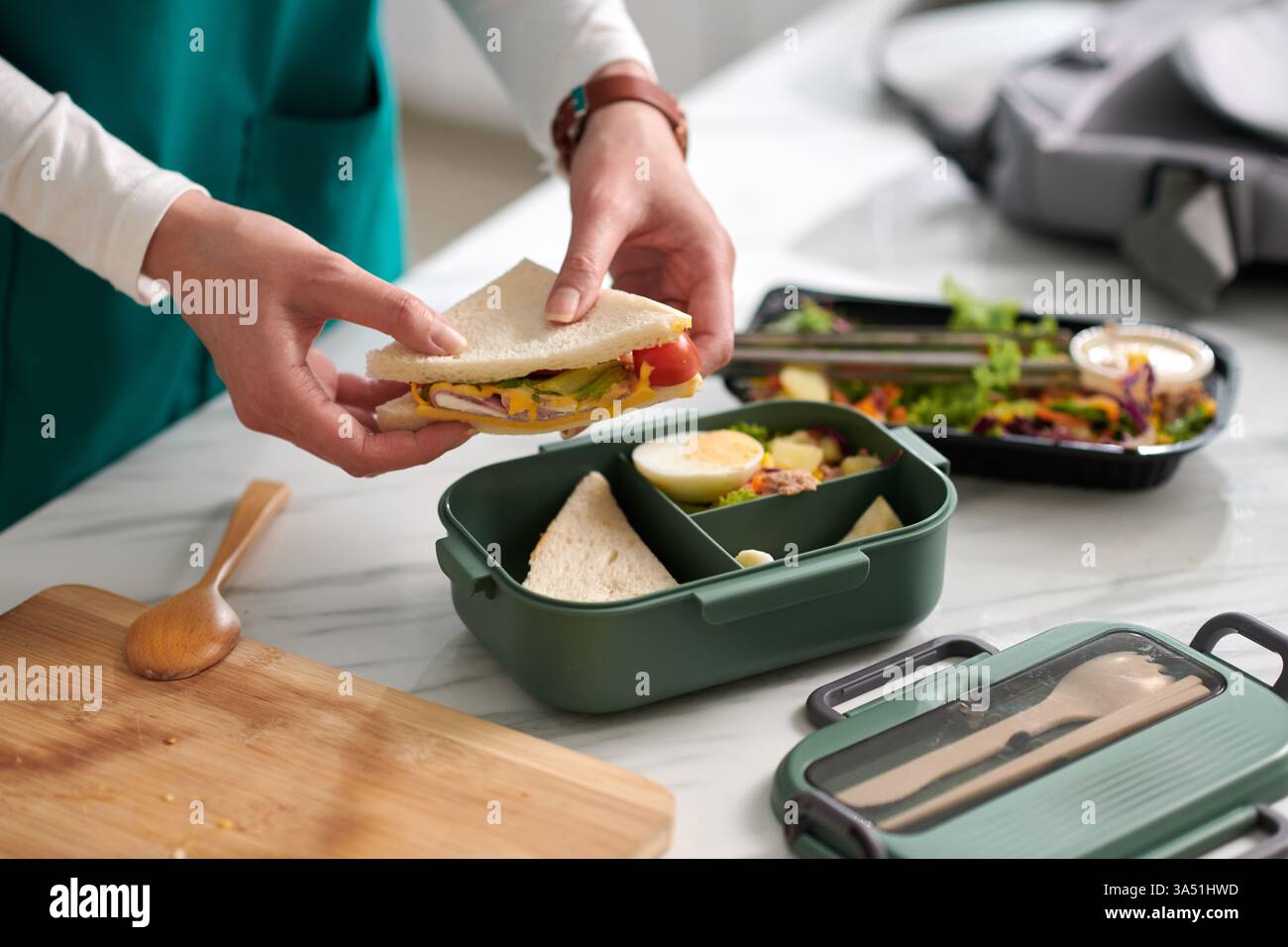 Nurse packing lunch for work, putting sandwich, salad and cut fruits in ...