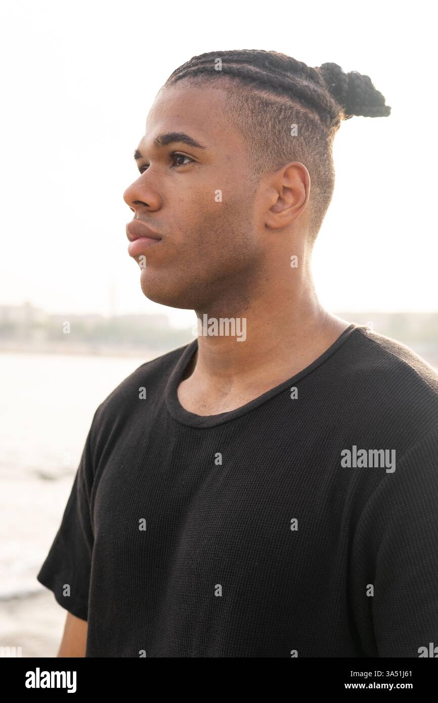 Hispanic male with braided hair standing on beach near sea during ...
