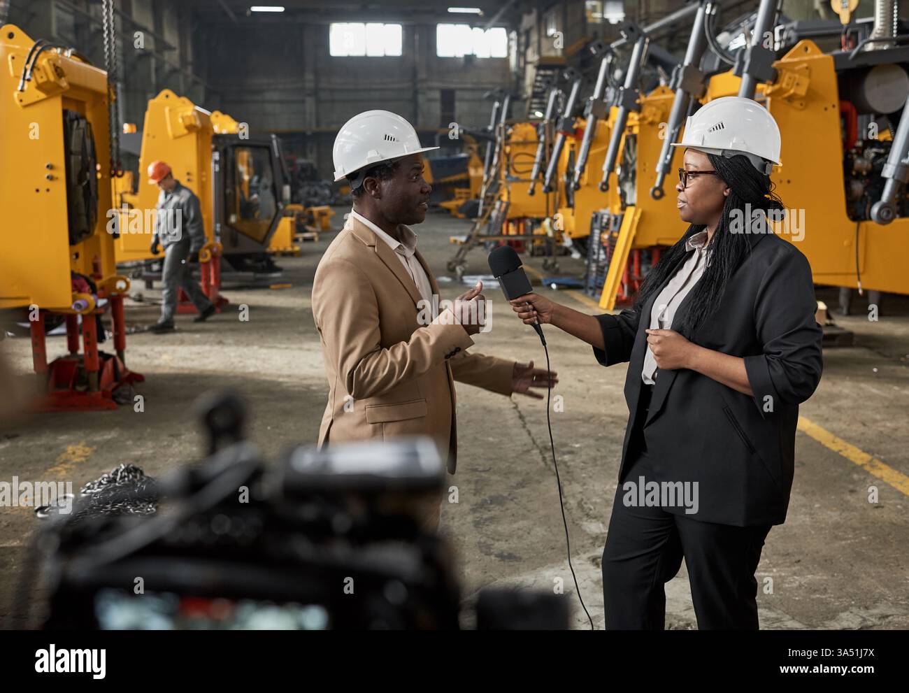 Black female journalist wearing safety helmet holding microphone ...