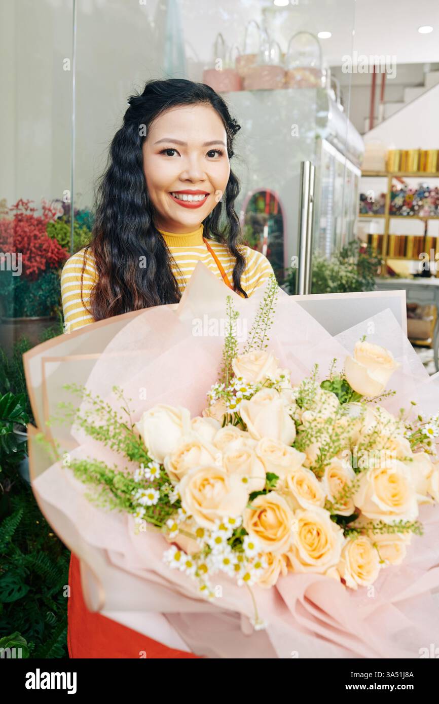 Portrait of Vietnamse flower shop owner standing with big bouquet of ...