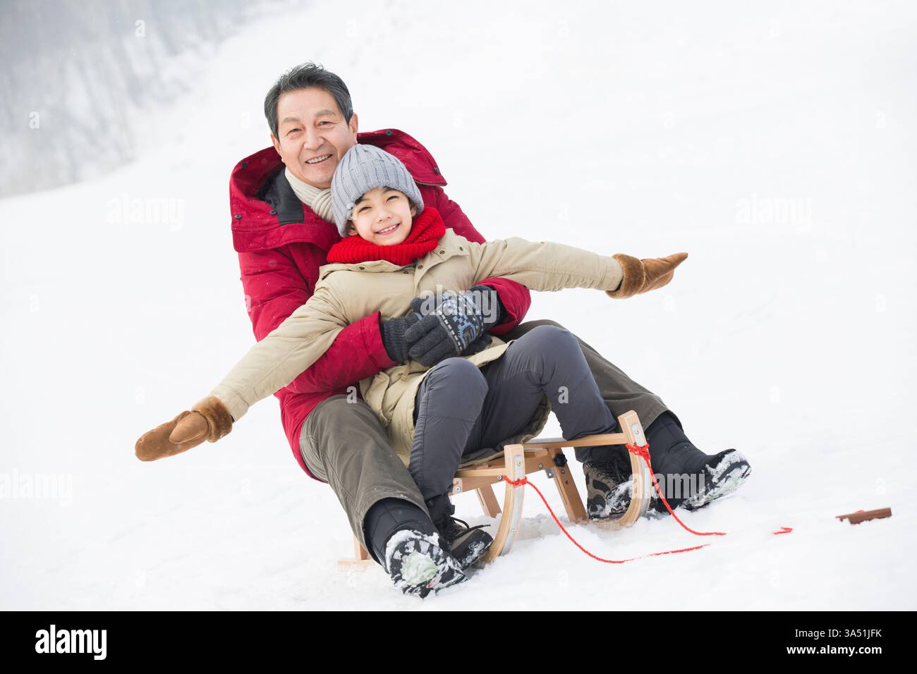 Chinese grandfather and grandson slide on a sled during winter ...